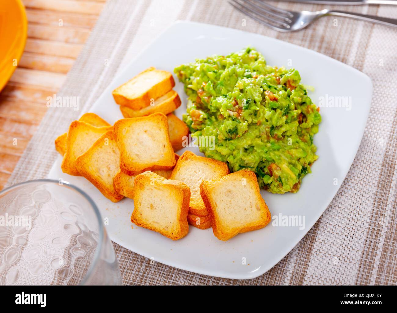 Guacamole and toasted bread served on white plate Stock Photo - Alamy