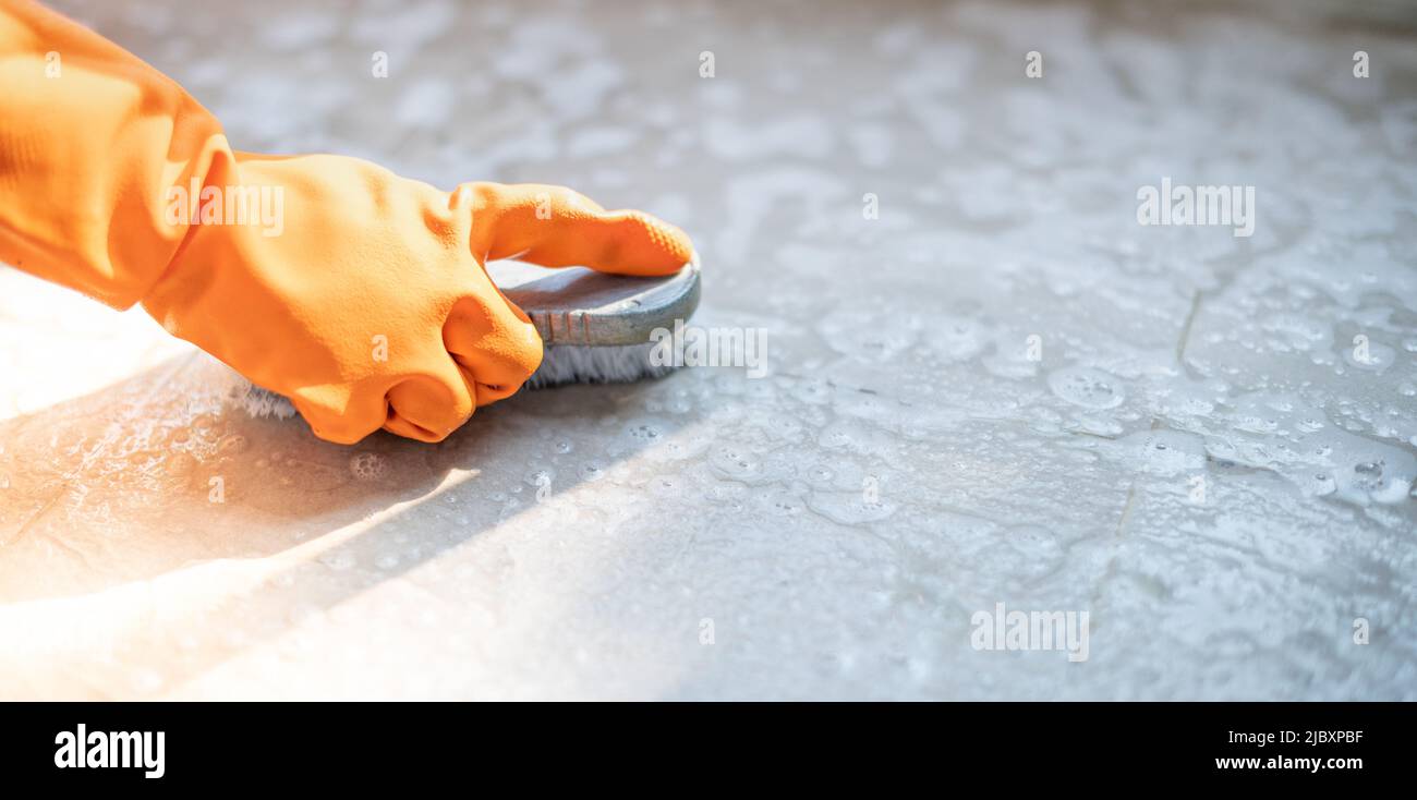 Female hand wearing the rubber glove and using the plastic brush for ...