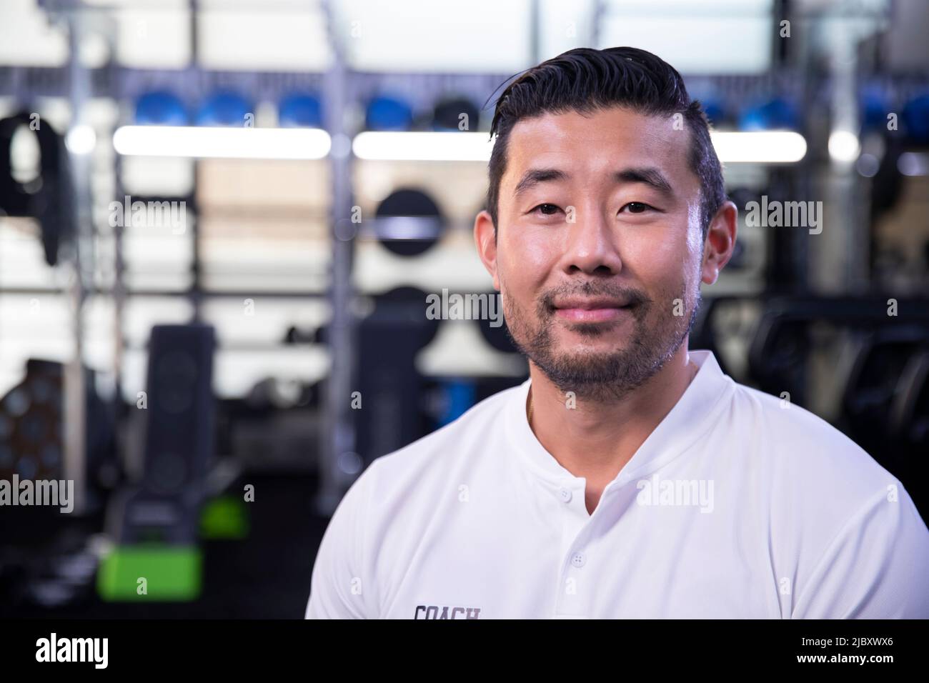 Portrait of an Asian American fitness coach looking into camera with a ...