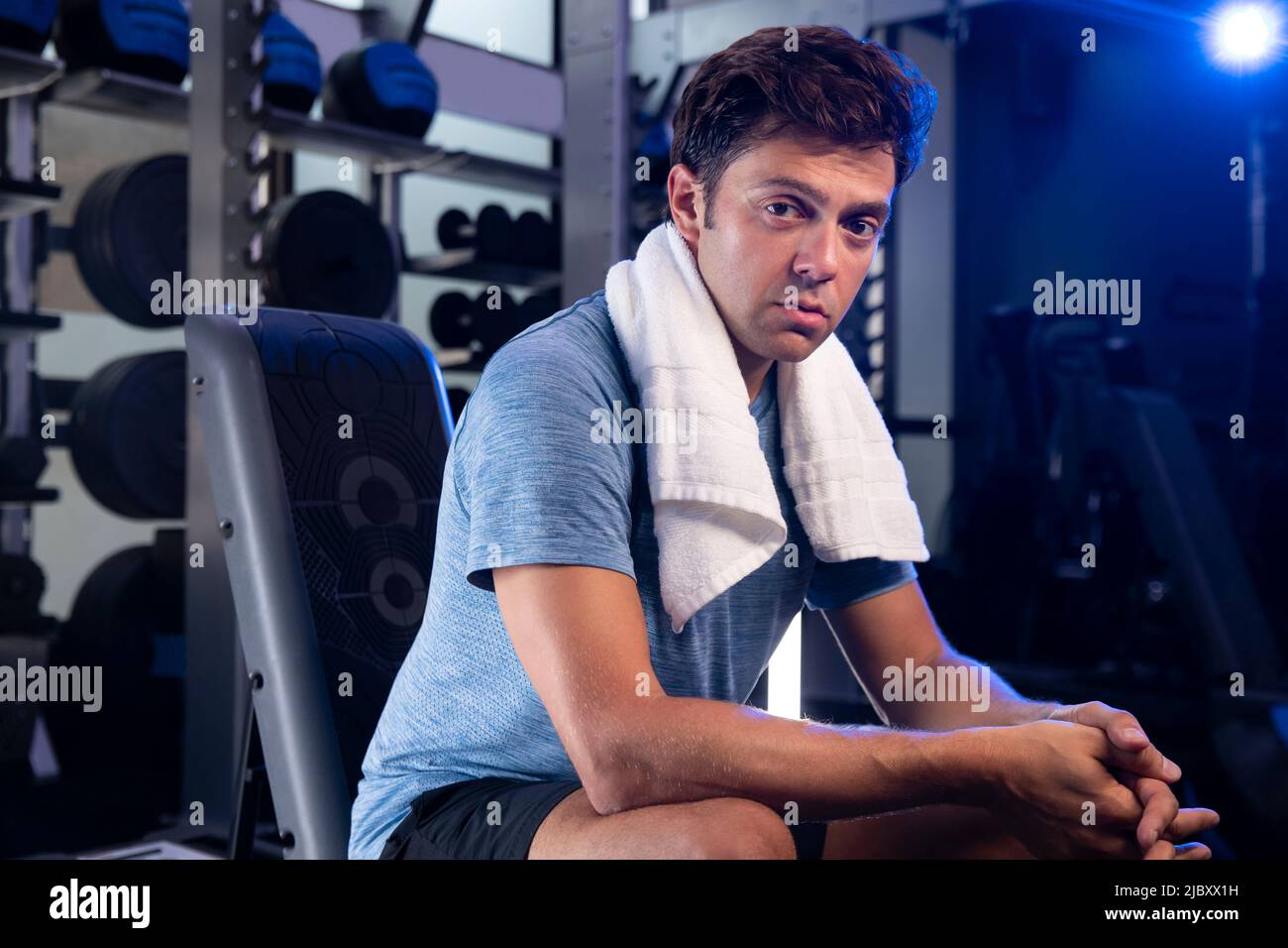 Fitness portrait of a young man resting after a long workout with towel ...