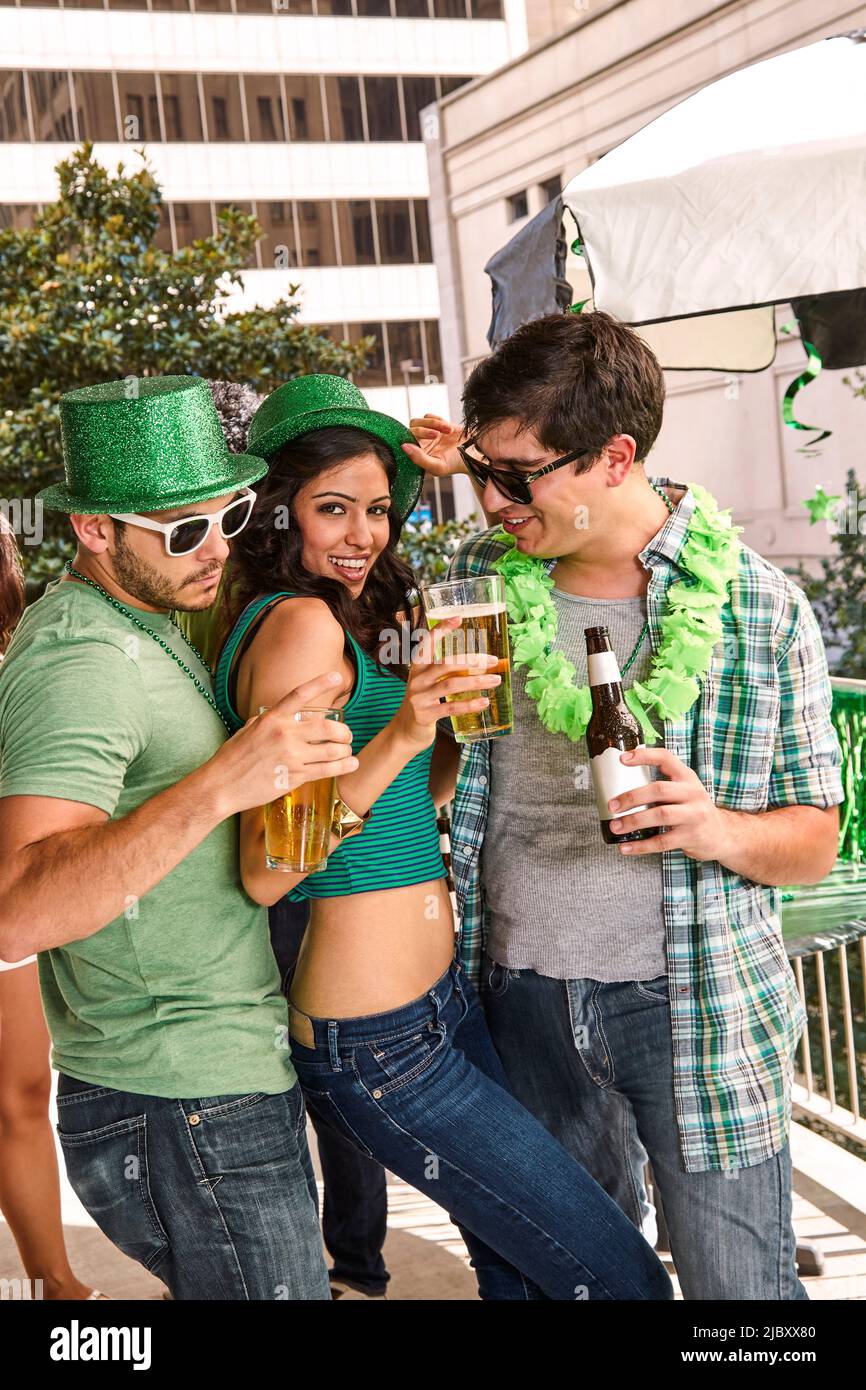 Group of three friends partying together on balcony during St Patrick's ...