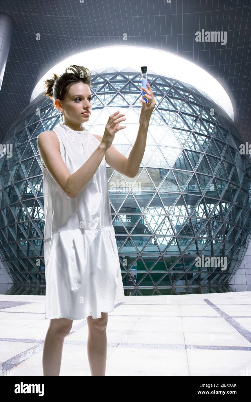 Young scientist inspecting test tube outside in front of geodesic dome ...