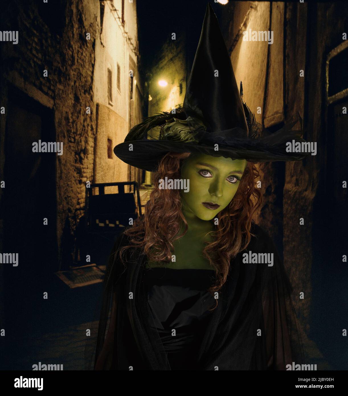 Young girl dressed as witch standing in front dark alley Stock Photo ...
