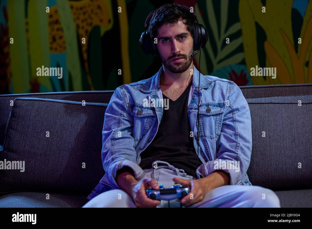 Man leaning back on couch with video game controller in hands, looking ...