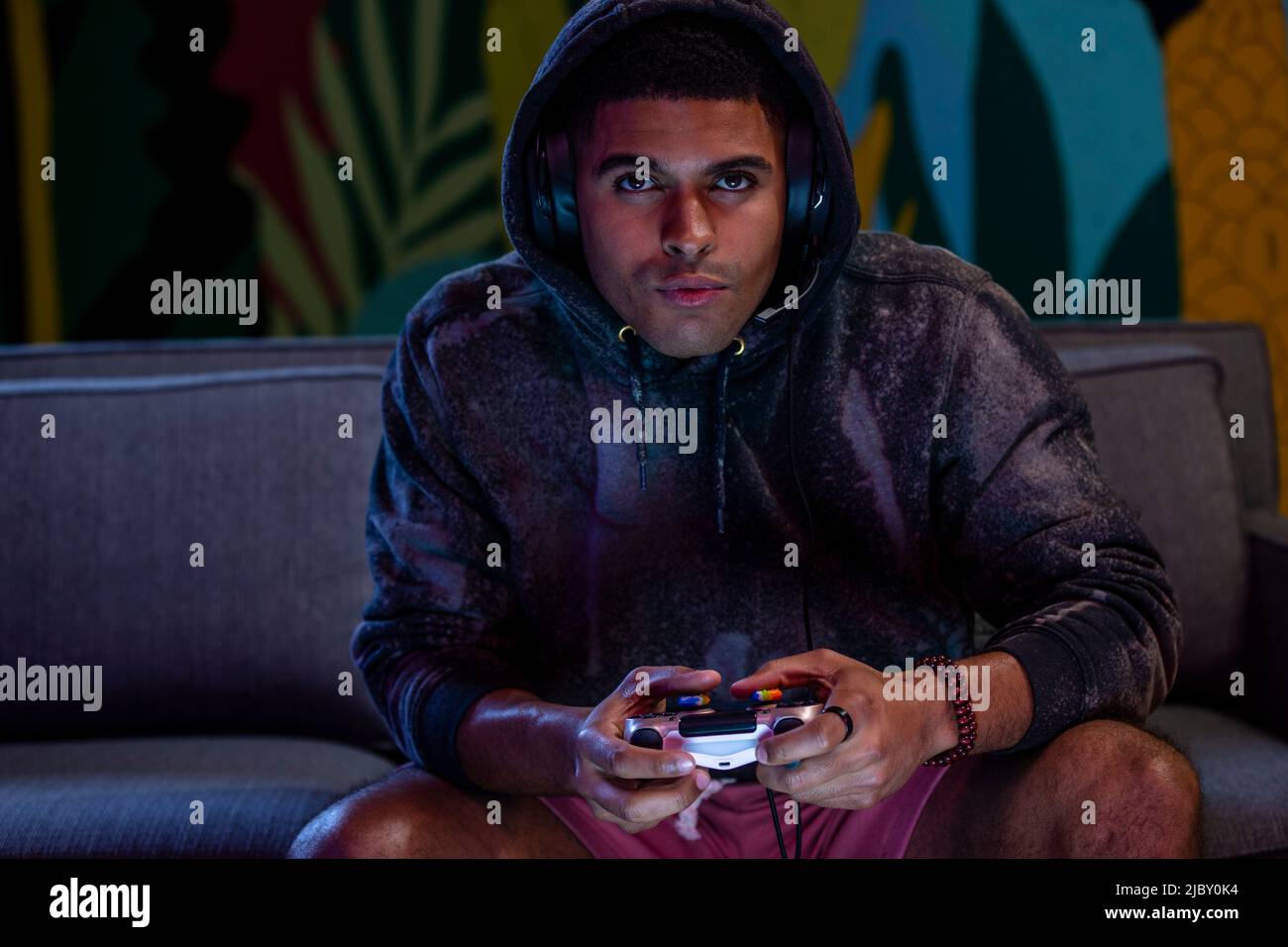 Young gamer man in hood playing game with game controller Stock Photo ...