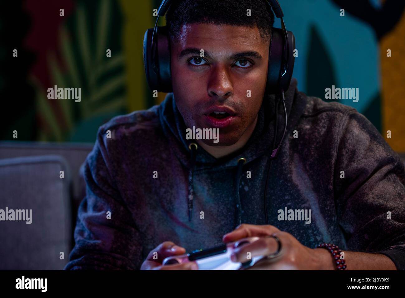Closeup of male African-American gamer wearing headphones while playing ...
