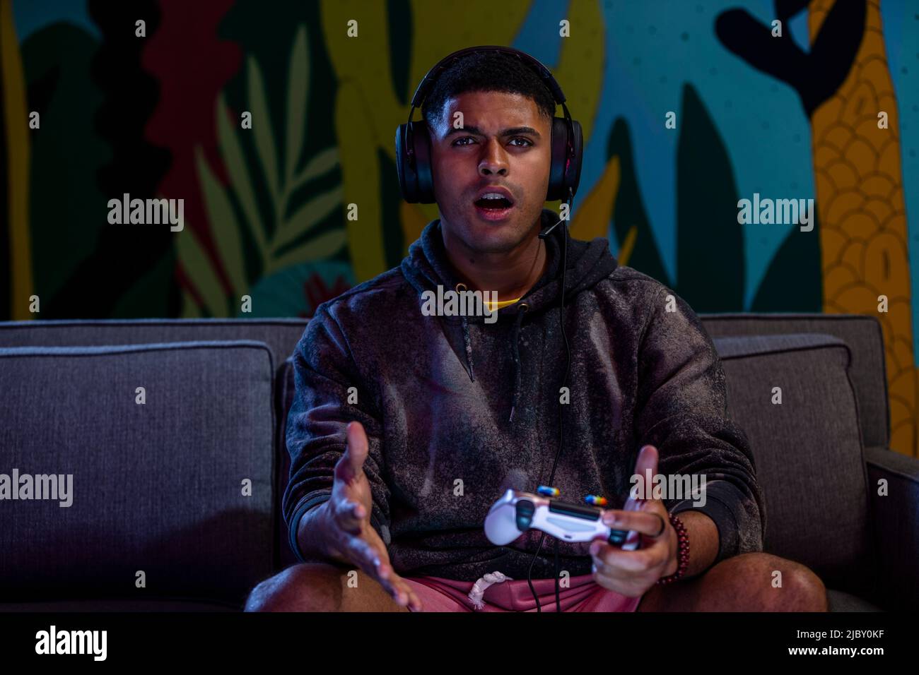 Young African-American man looking shocked while playing video games ...