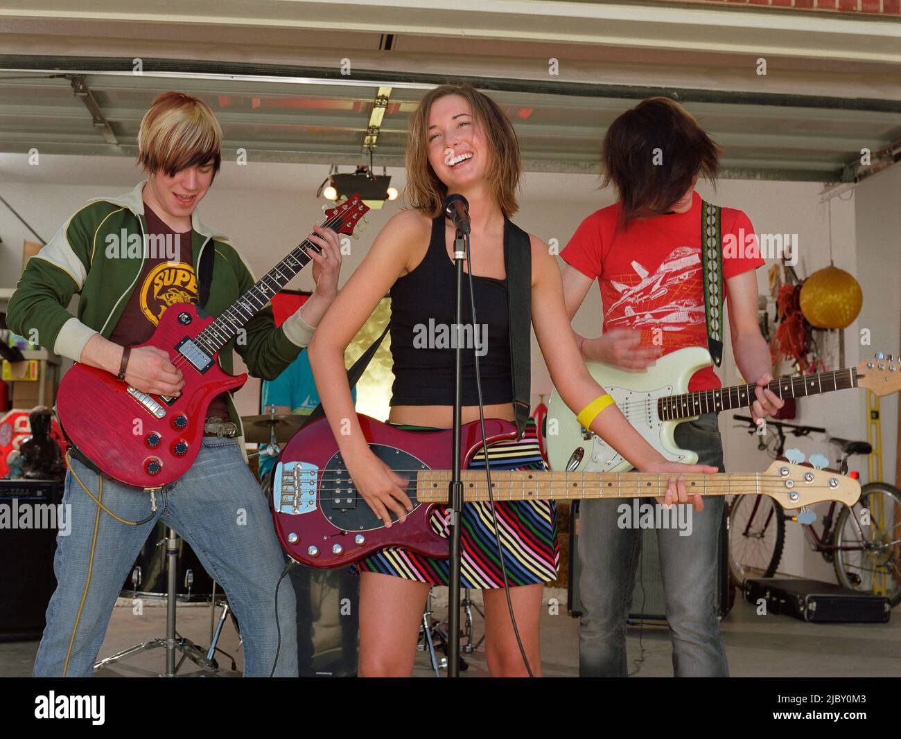 Group of Friends in garage band practicing in driveway in front of home ...