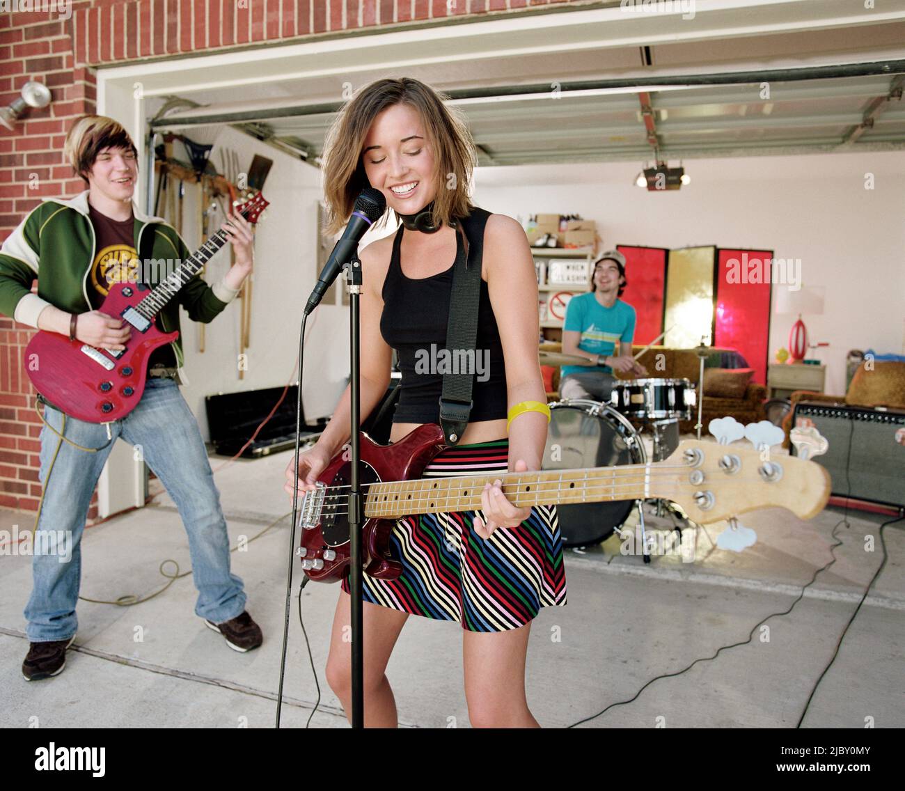 Group of Friends in garage band practicing in driveway in front of home ...
