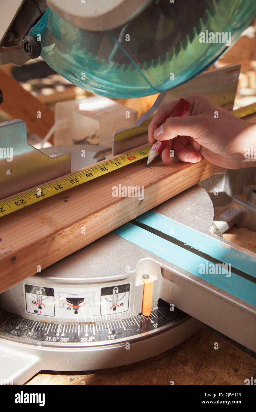 Man marking his measurement on a piece of wood before cutting it with a ...