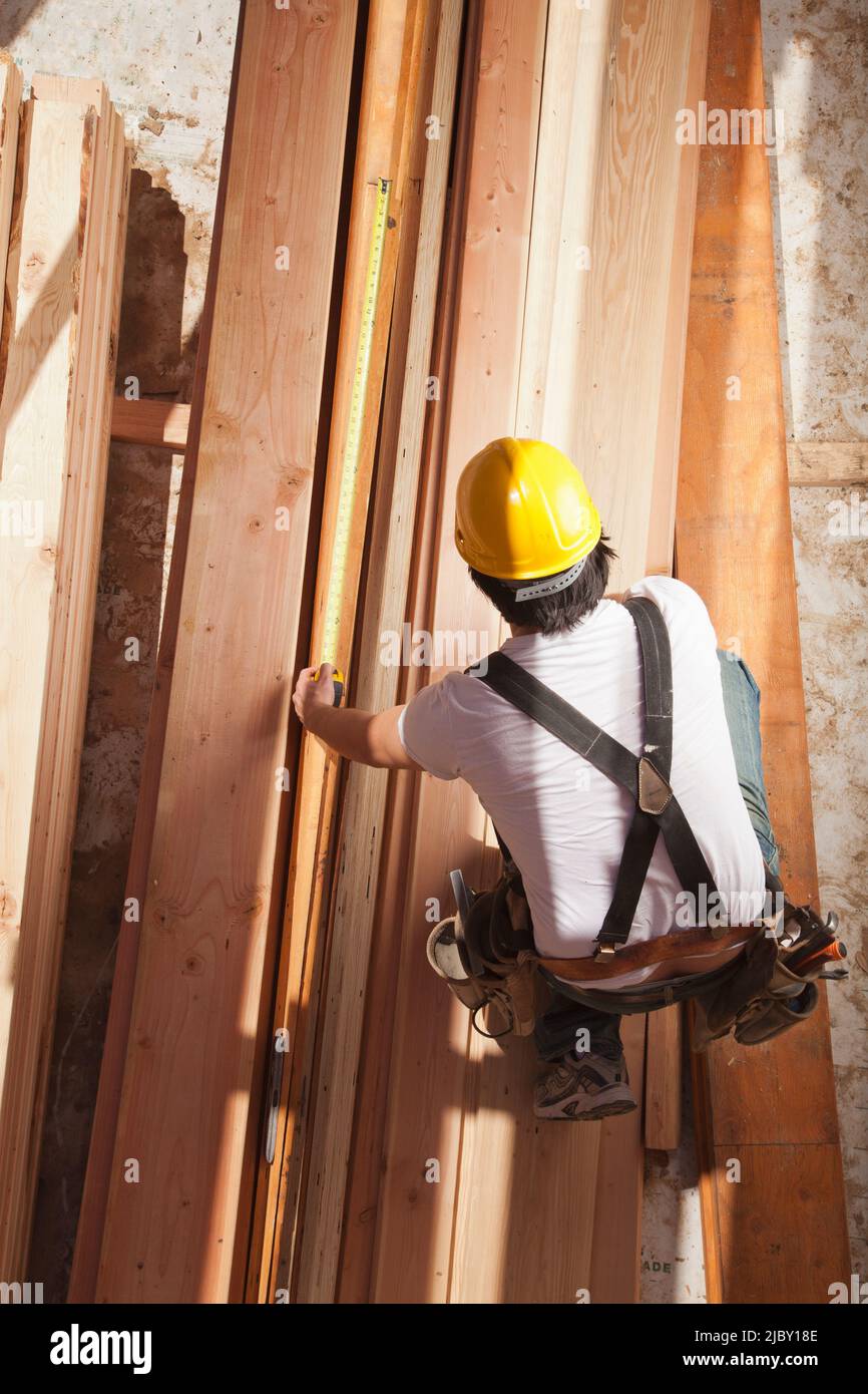 Aerial view of a man measuring wood on a residential construction site ...