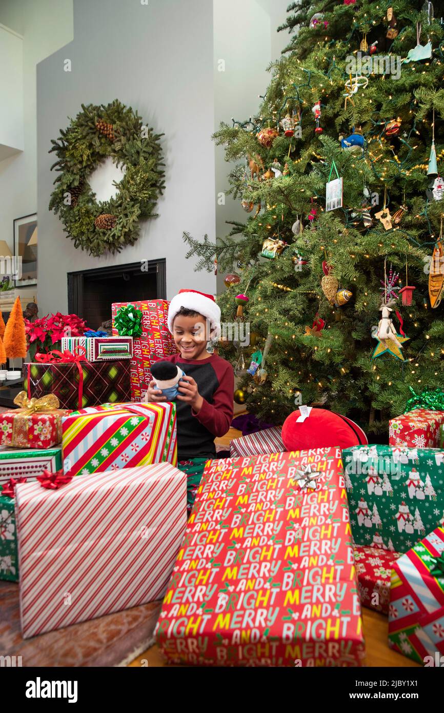 Boy opening gift under tree on Christmas morning Stock Photo - Alamy