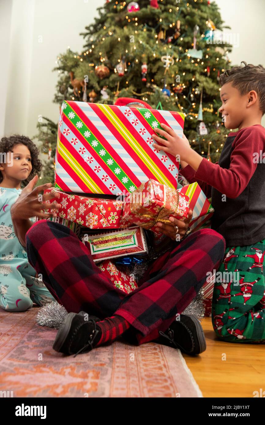 Kids stacking up Christmas gifts on their dad's lap Stock Photo - Alamy