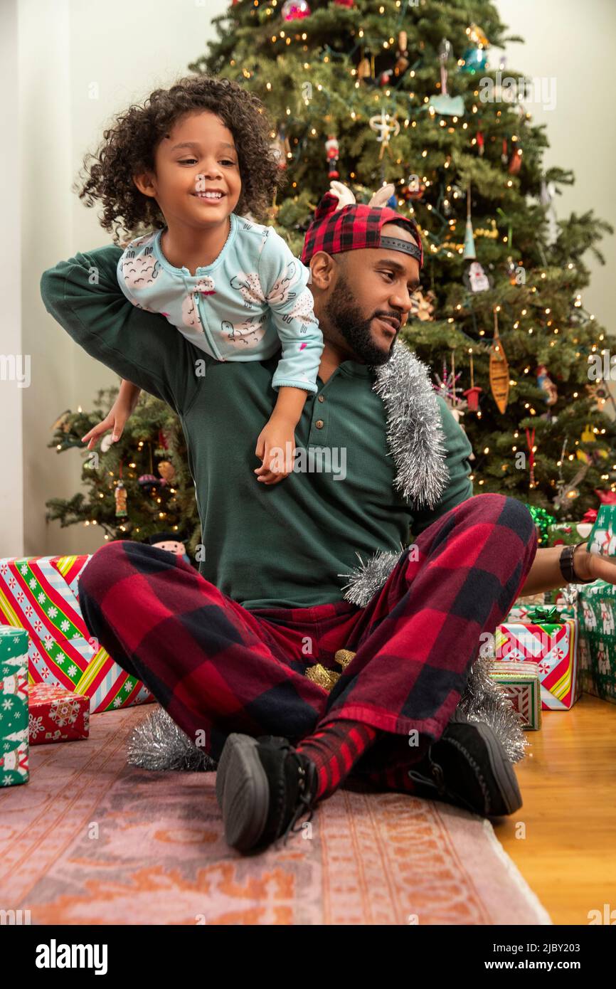 Happy family with Christmas presents sitting in front of illuminated ...