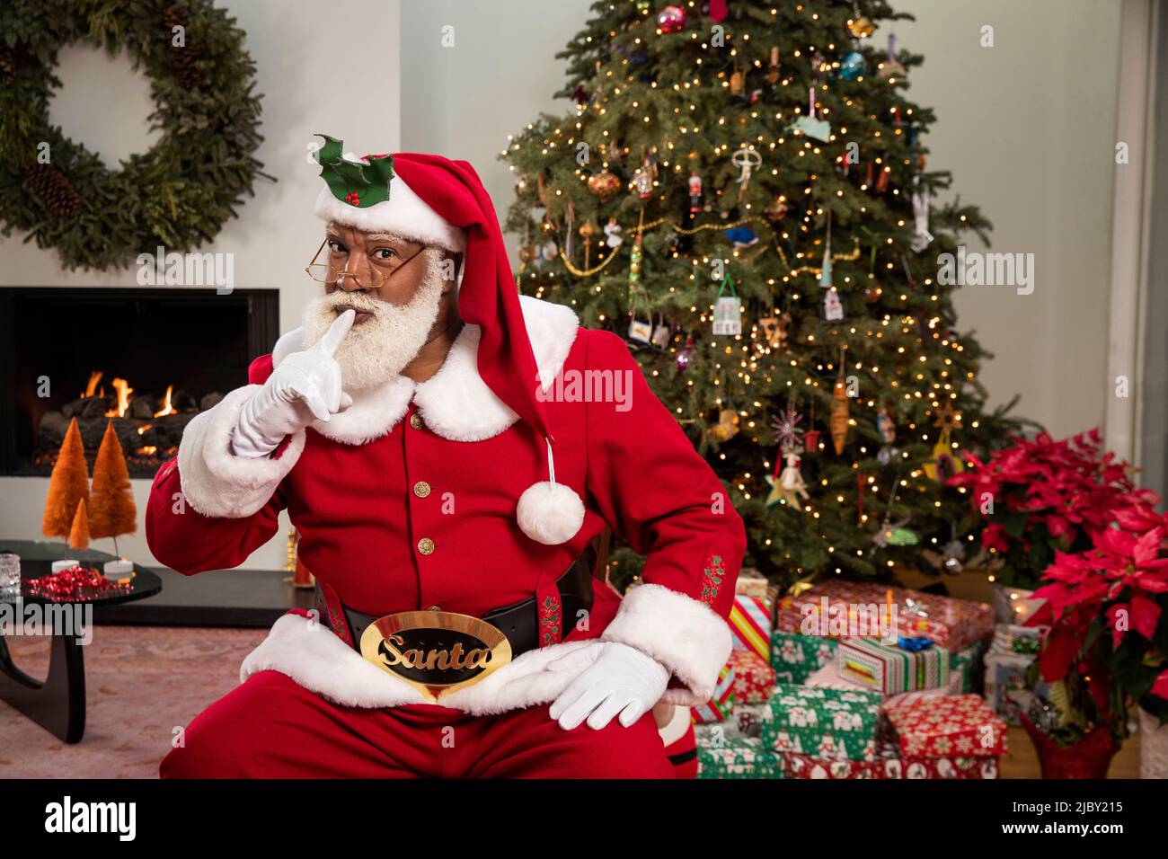 Santa Clause sitting in living room making a quiet gesture at camera ...