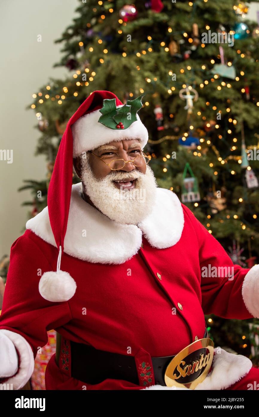 Elderly man dressed as Black Santa with his arms open towards camera ...