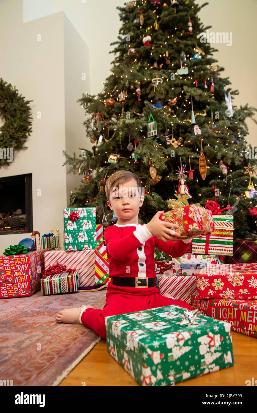 Yong boy shaking his Christmas gift with curiosity Stock Photo - Alamy