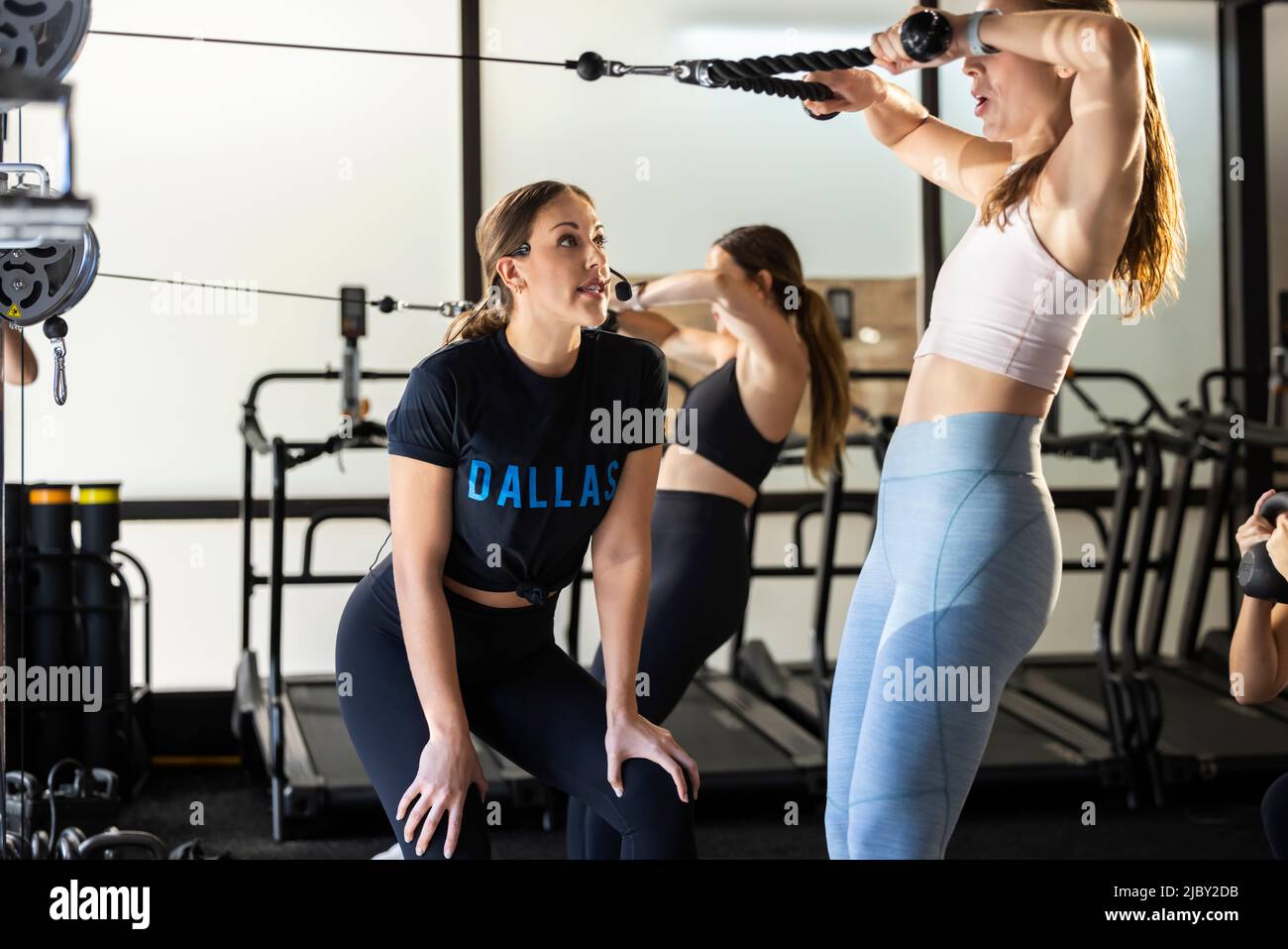 Woman working out on exercise machine, with her personal trainer in ...