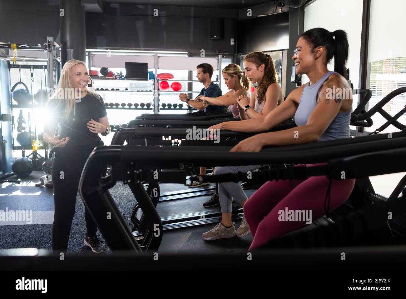 Happy fitness instructor talking to her class while they do exercises ...
