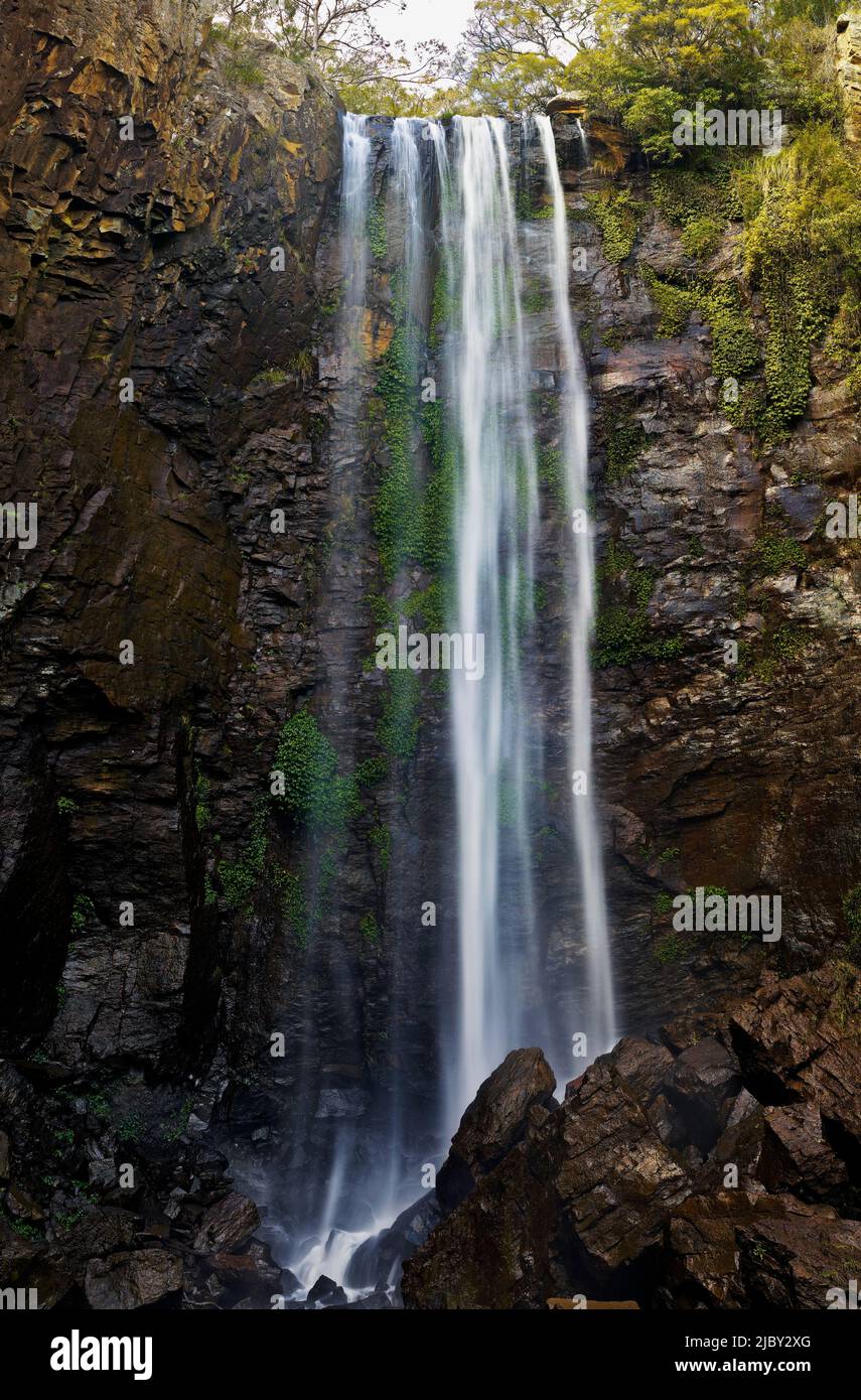 Water falling down rocky cliff face onto rocks below at Queen Mary ...