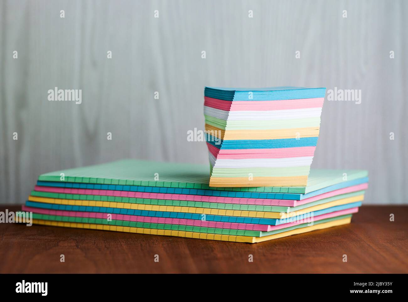 Different coloured note paper and pads stacked on wooden desk Stock ...