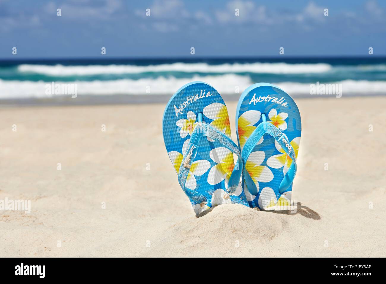 A pair of thongs standing upright in the sand at the beach Stock Photo ...