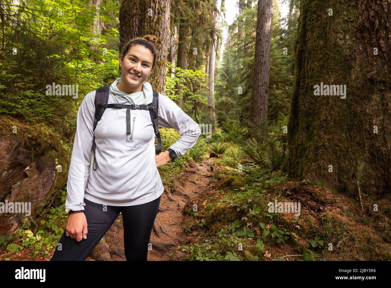 Portrait of young Caucasian woman standing along hiking trail in Hoh ...