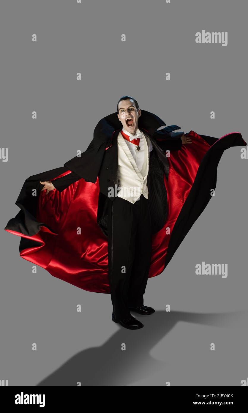 A vampire against a gray background holding his arms out at camera with ...