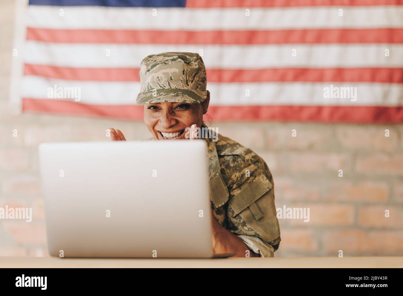 Courageous female soldier smiling happily while video chatting with her ...