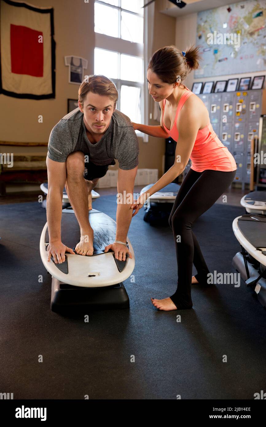 A yoga instructor helping a student with a yoga pose on top of a ...