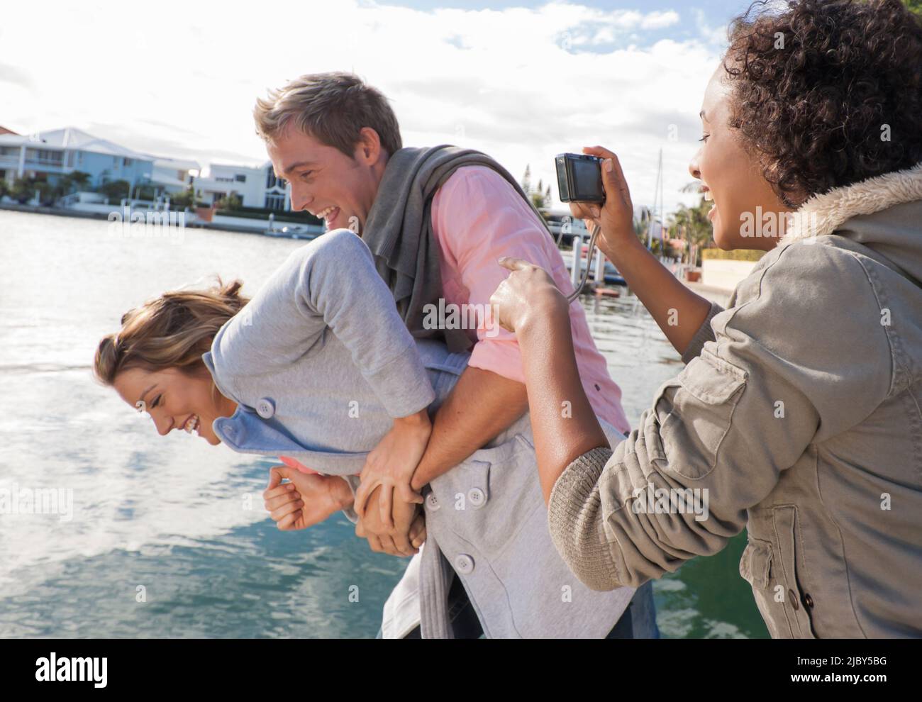 Young woman taking pictures of friends fooling around by water Stock ...