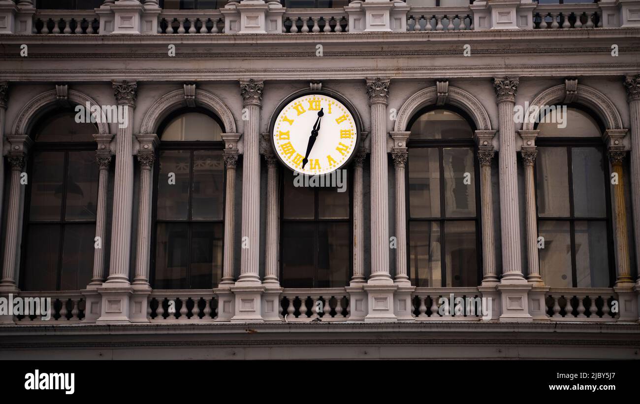 A traditional analog clock with yellow numbers on the front of an old ...