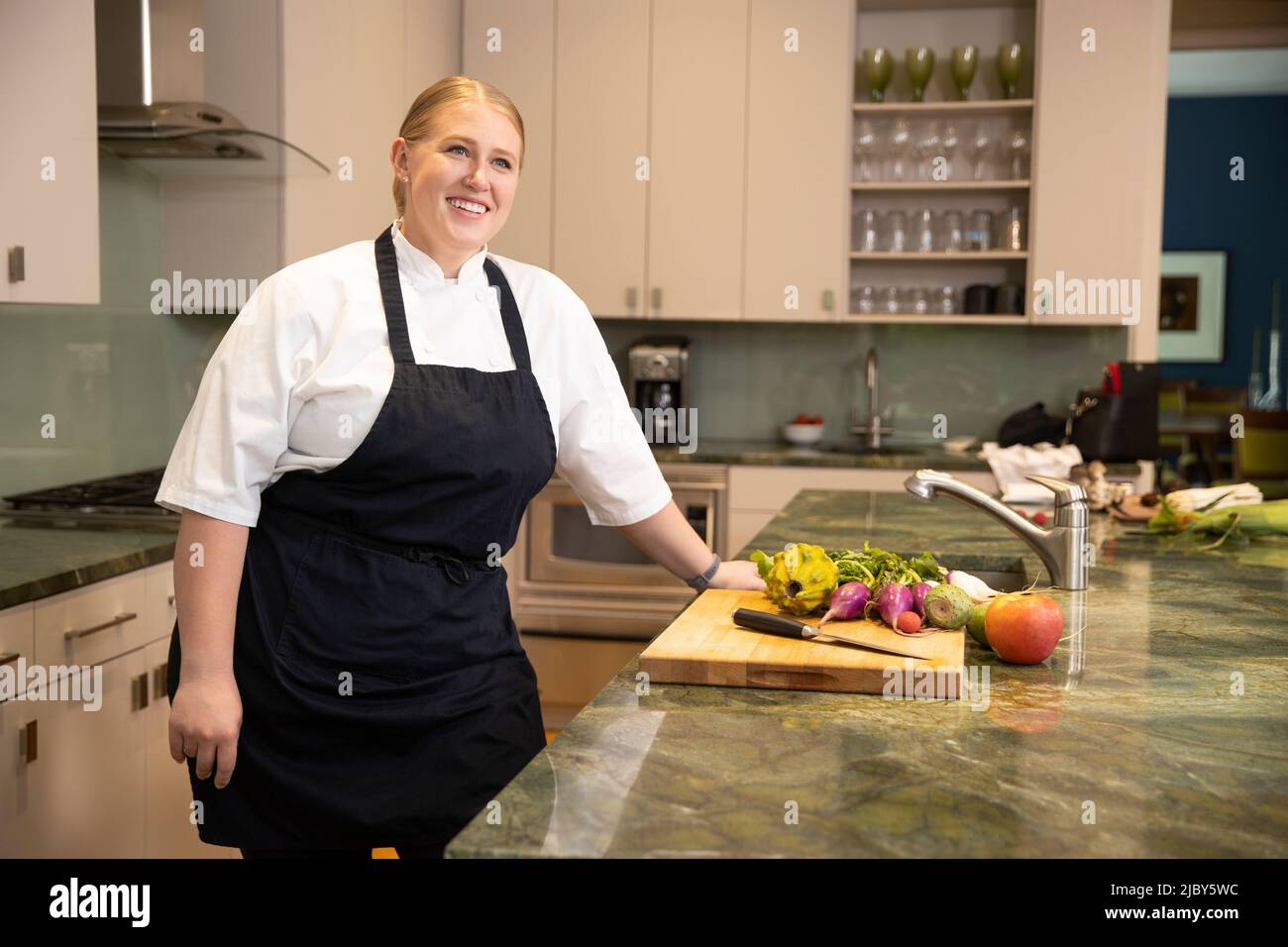 Portrait of Chef Megan Gill in kitchen looking up off camera, smiling ...