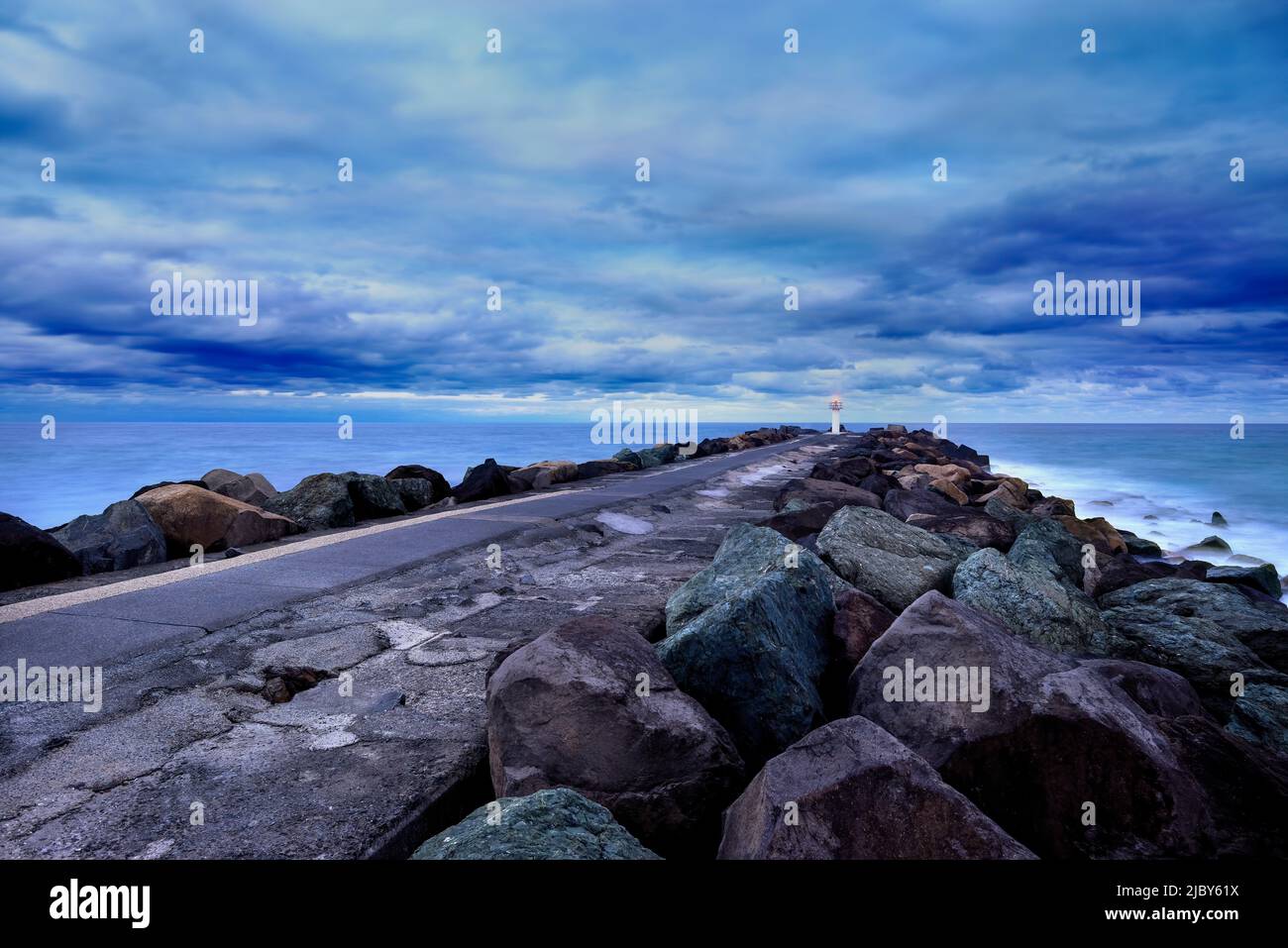 Looking down length of rocky breakwater leading out to the ocean in ...