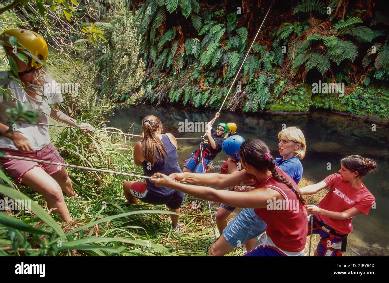 Team building using ropes to cross river Stock Photo - Alamy