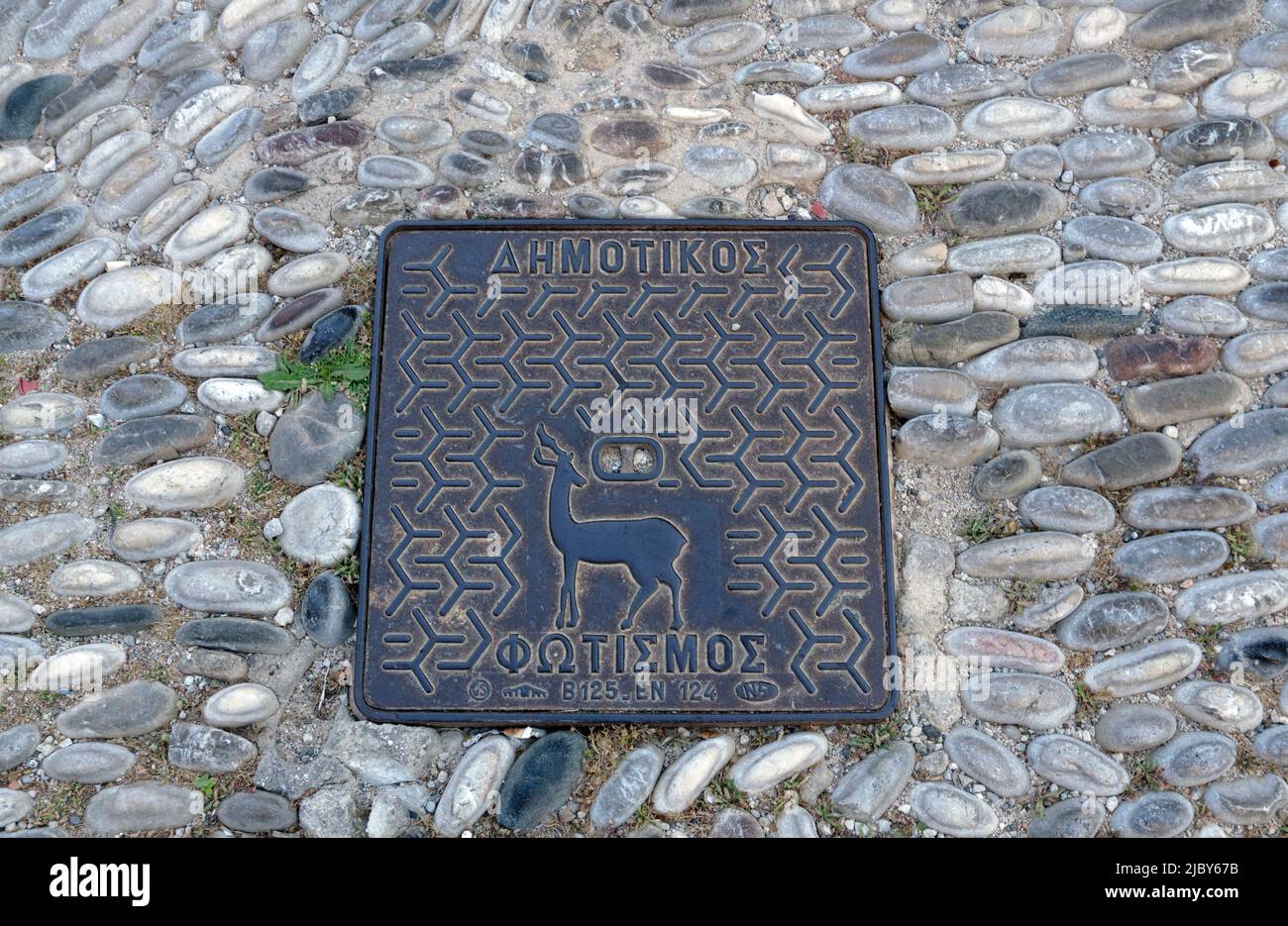 Drain / manhole cover with deer. Beach stone cobbles. Rhodes Old Town ...