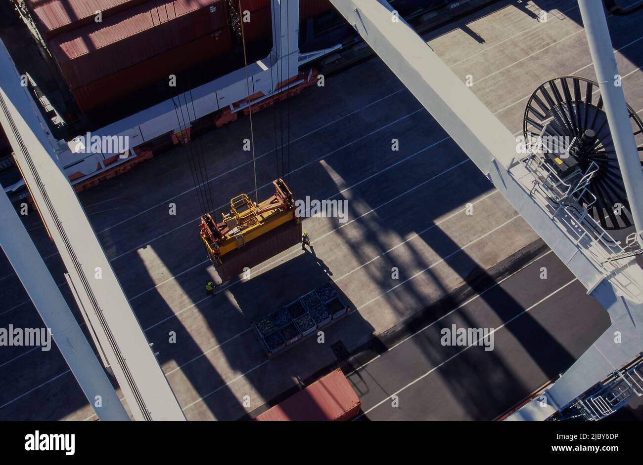 Looking down from crane at shipping container being secured for loading ...