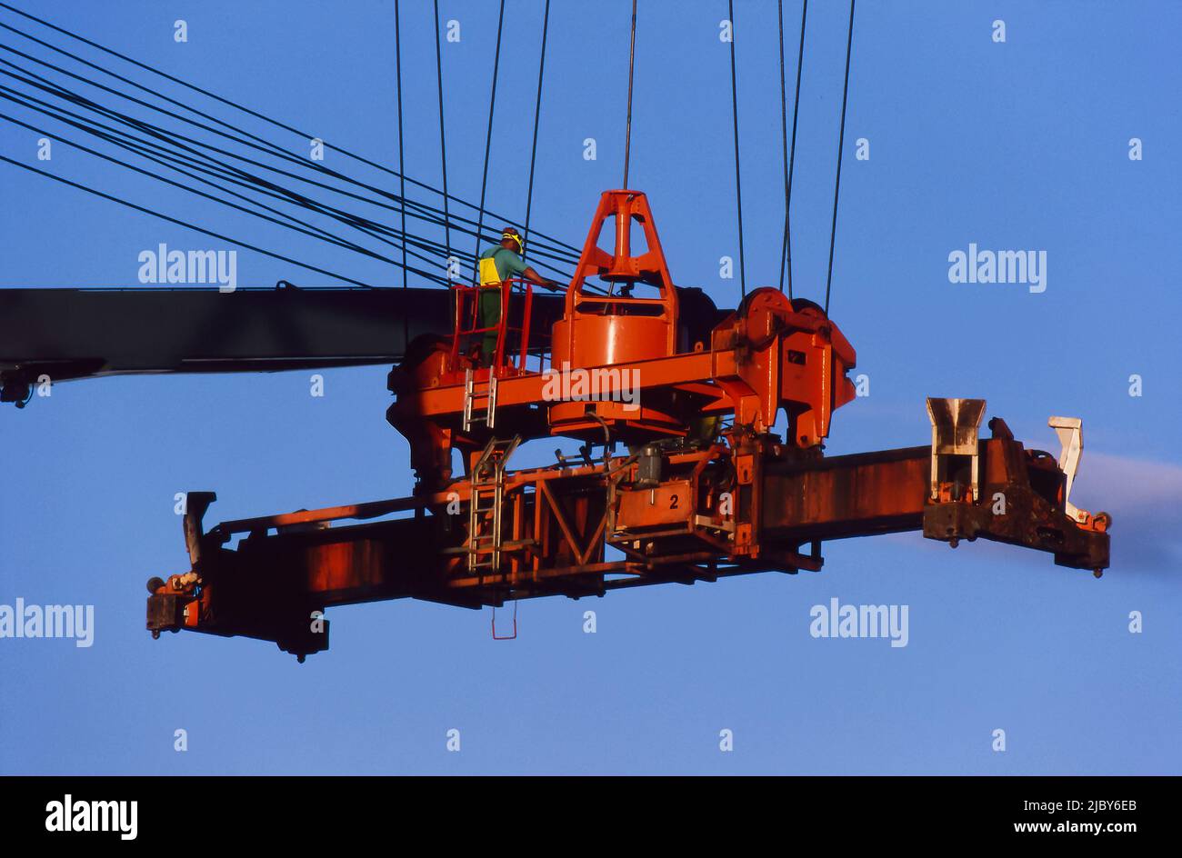 Man operating crane to load and unload shipping containers at the port ...