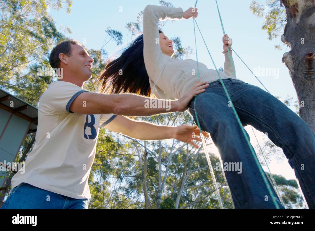 Man pushing woman on a swing Stock Photo - Alamy