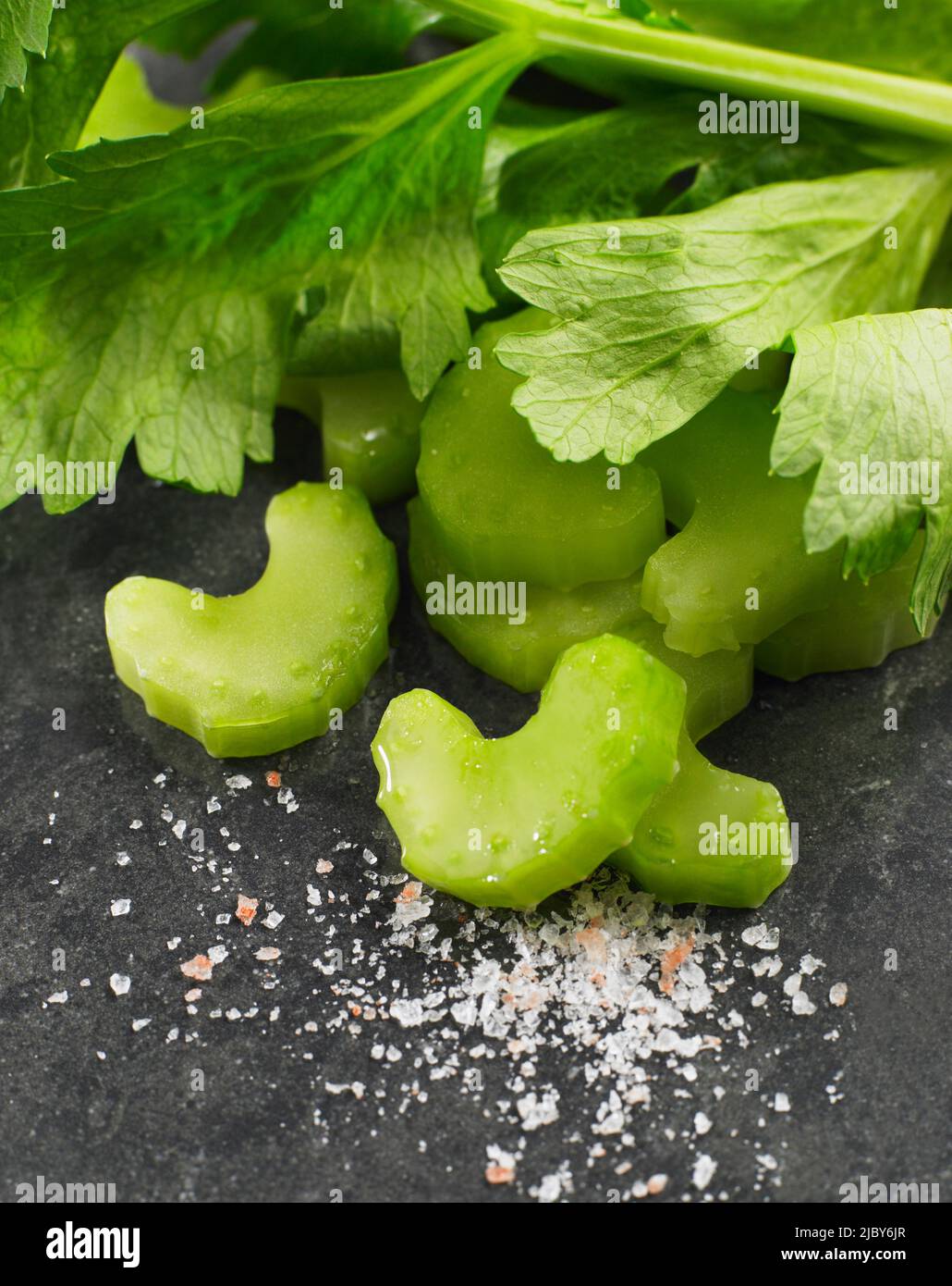 Celery stalks and sliced celery sprinkled with rock salt on black ...