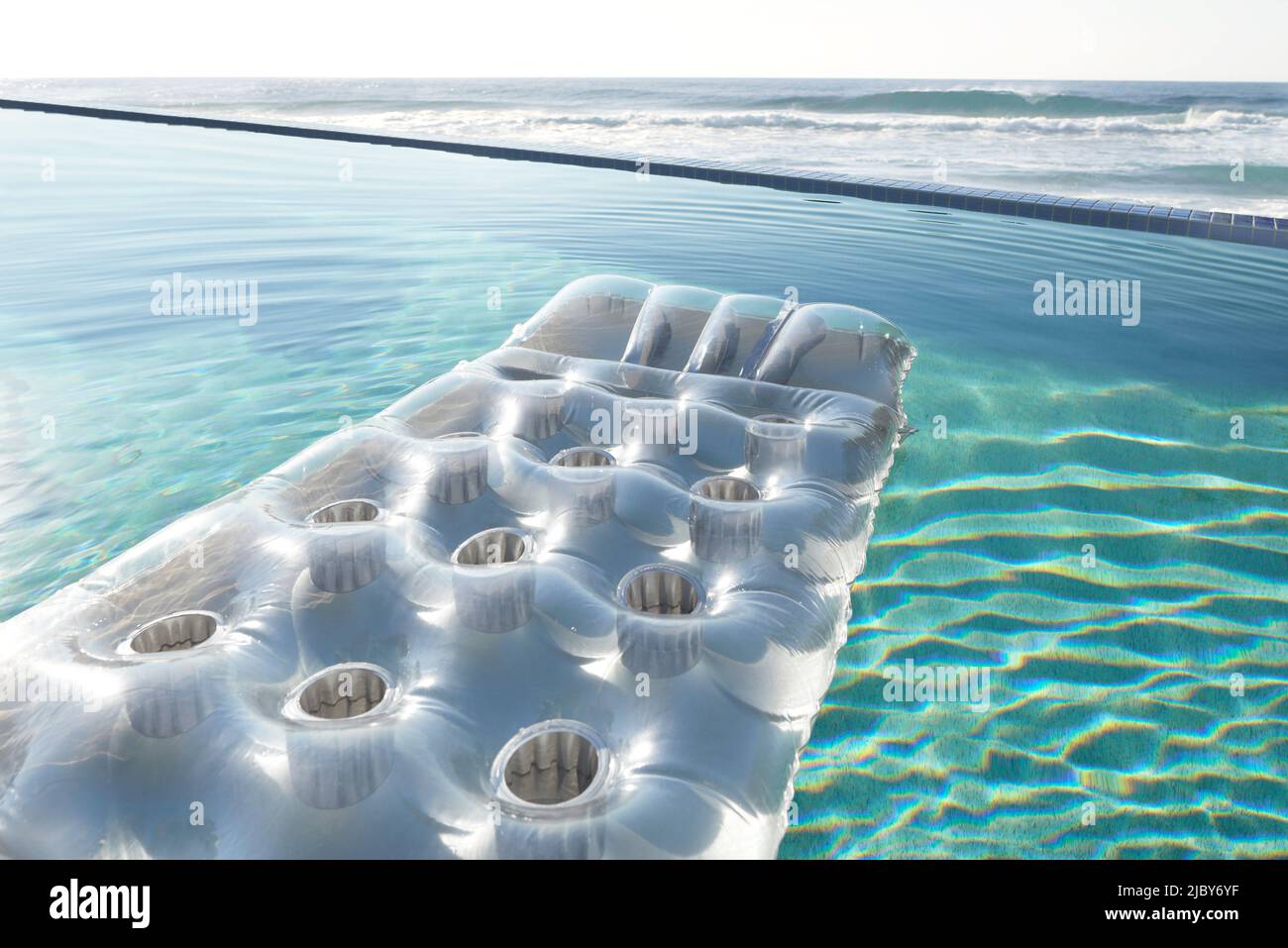 Lilo floating in swimming pool with view of waves rolling in at the ...