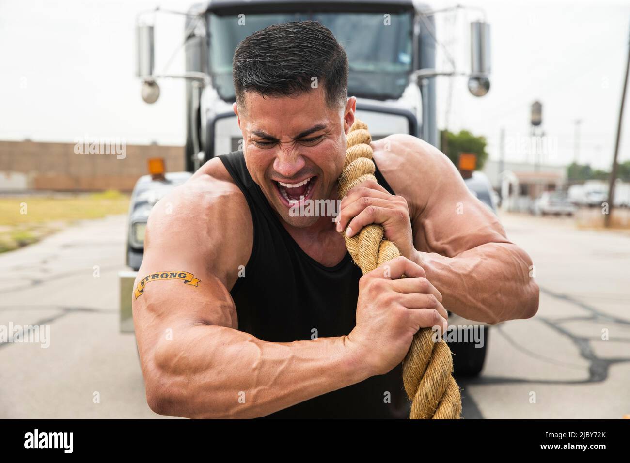 Muscular Hispanic man wearing tank top with “Strong” tattoo on his ...