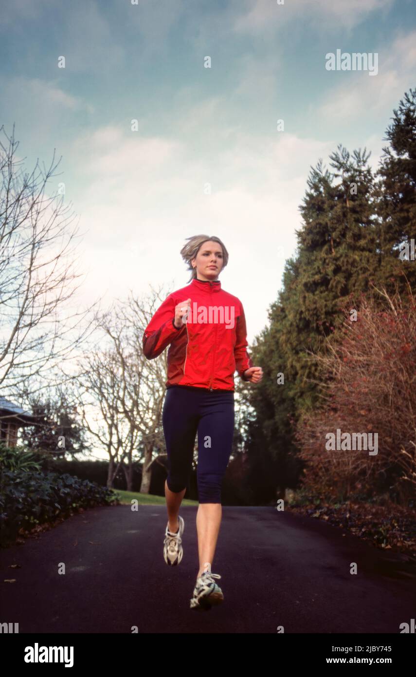 Woman running down driveway of home heading out for a run Stock Photo ...