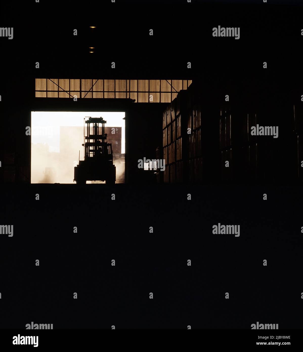 Forklift leaving industrial warehouse entrance with shipping container ...