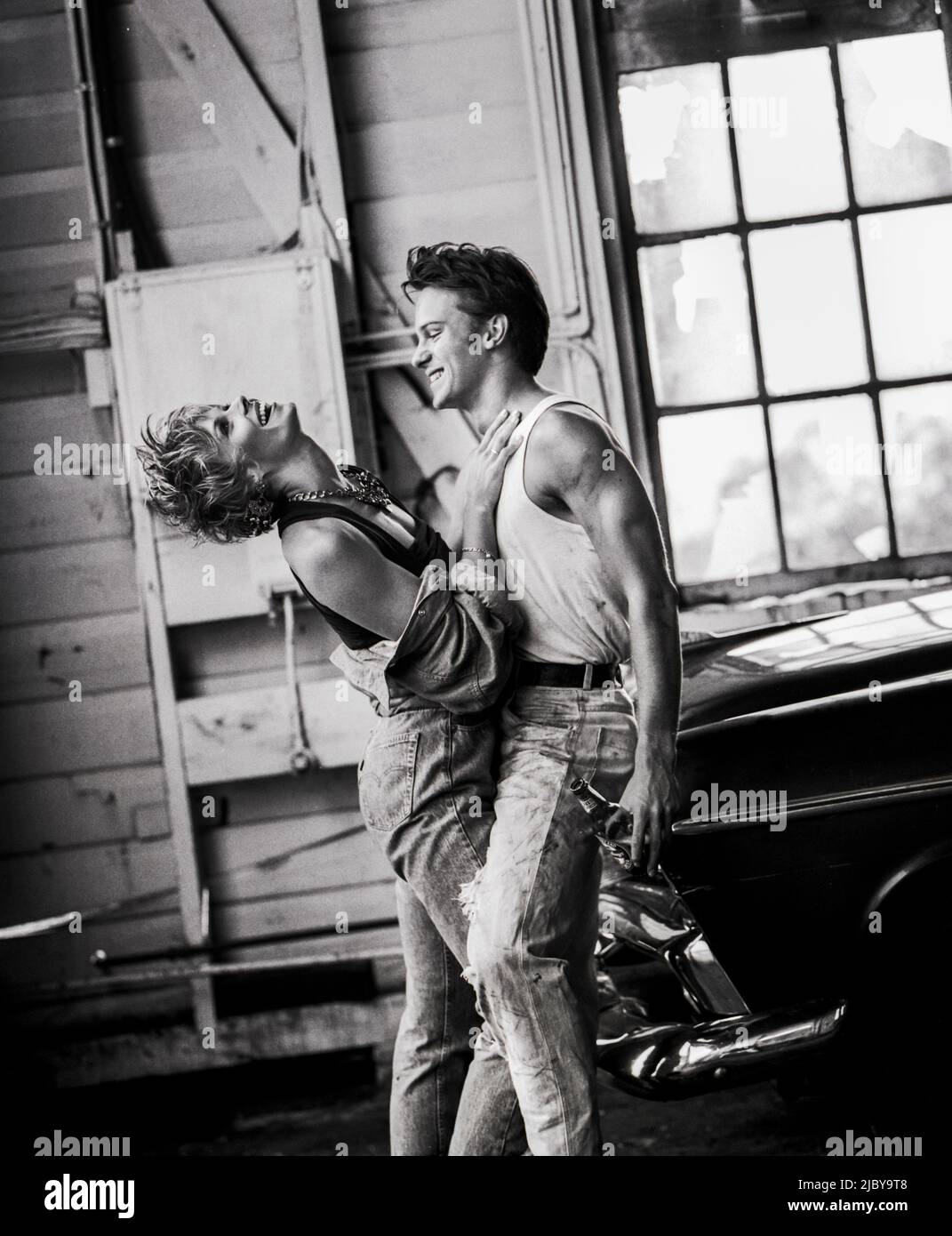 Young mechanic and his girlfriend cuddlind and laughing in workshop ...