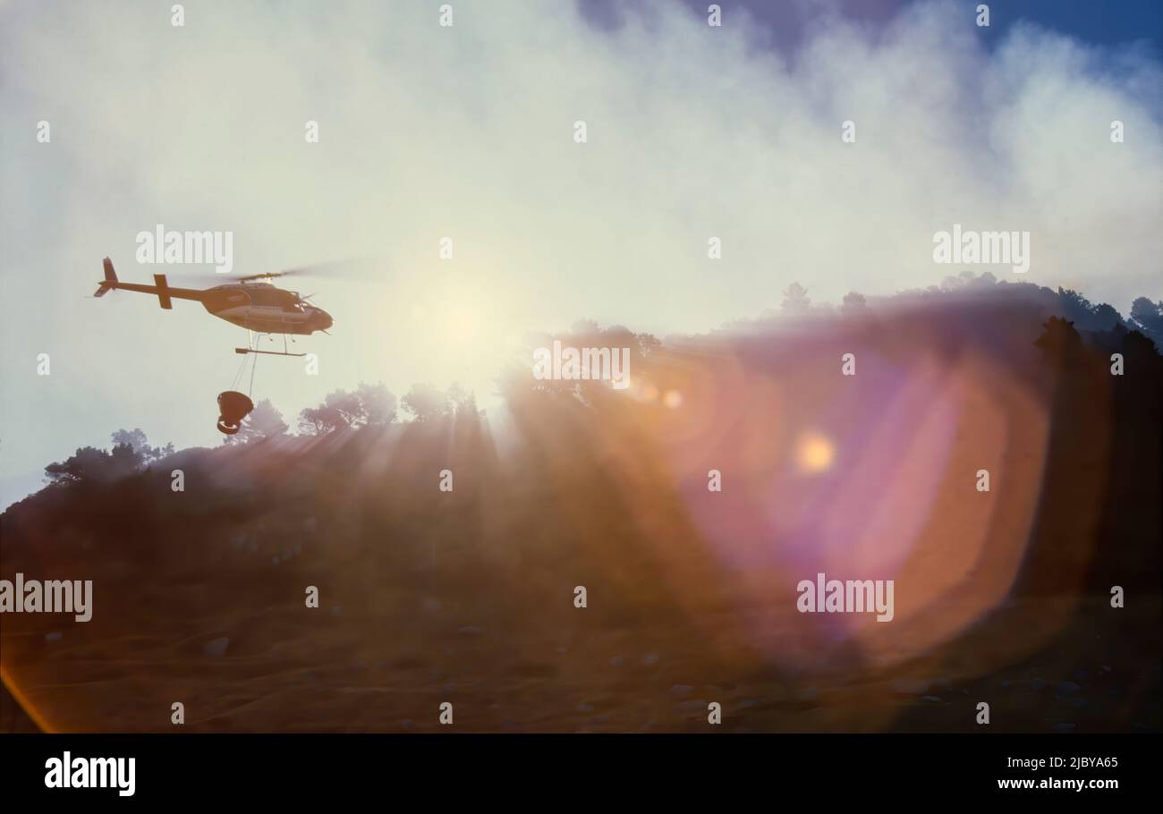 Helicopter with monsoon bucket full of water heading towards bush fire ...