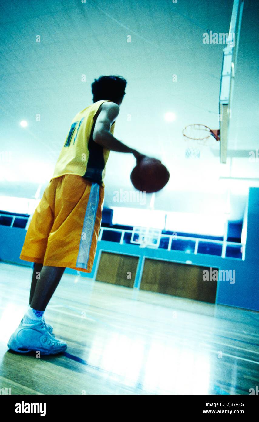 Student bouncing basketball in college gymnasium Stock Photo - Alamy