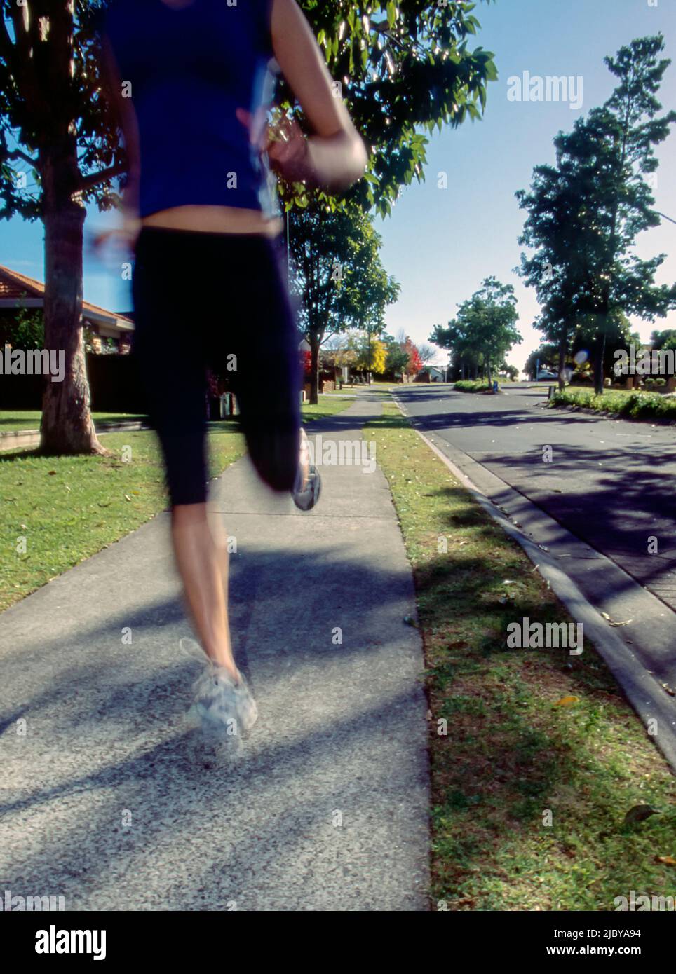 Woman running along residential street Stock Photo - Alamy