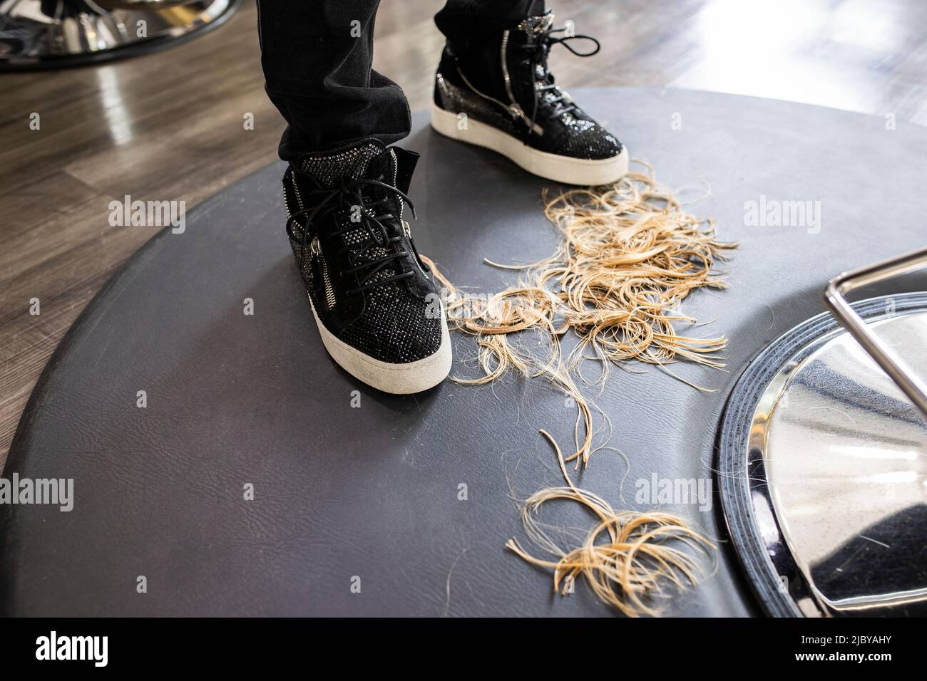Detail of clipped hair at feet of stylist on floor below chair at ...