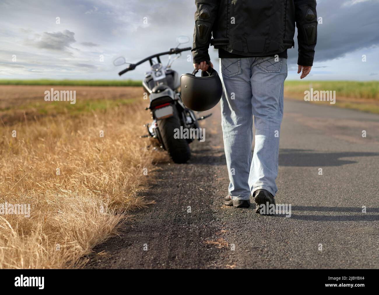 Man walking towards his motorbike parked on country road Stock Photo ...